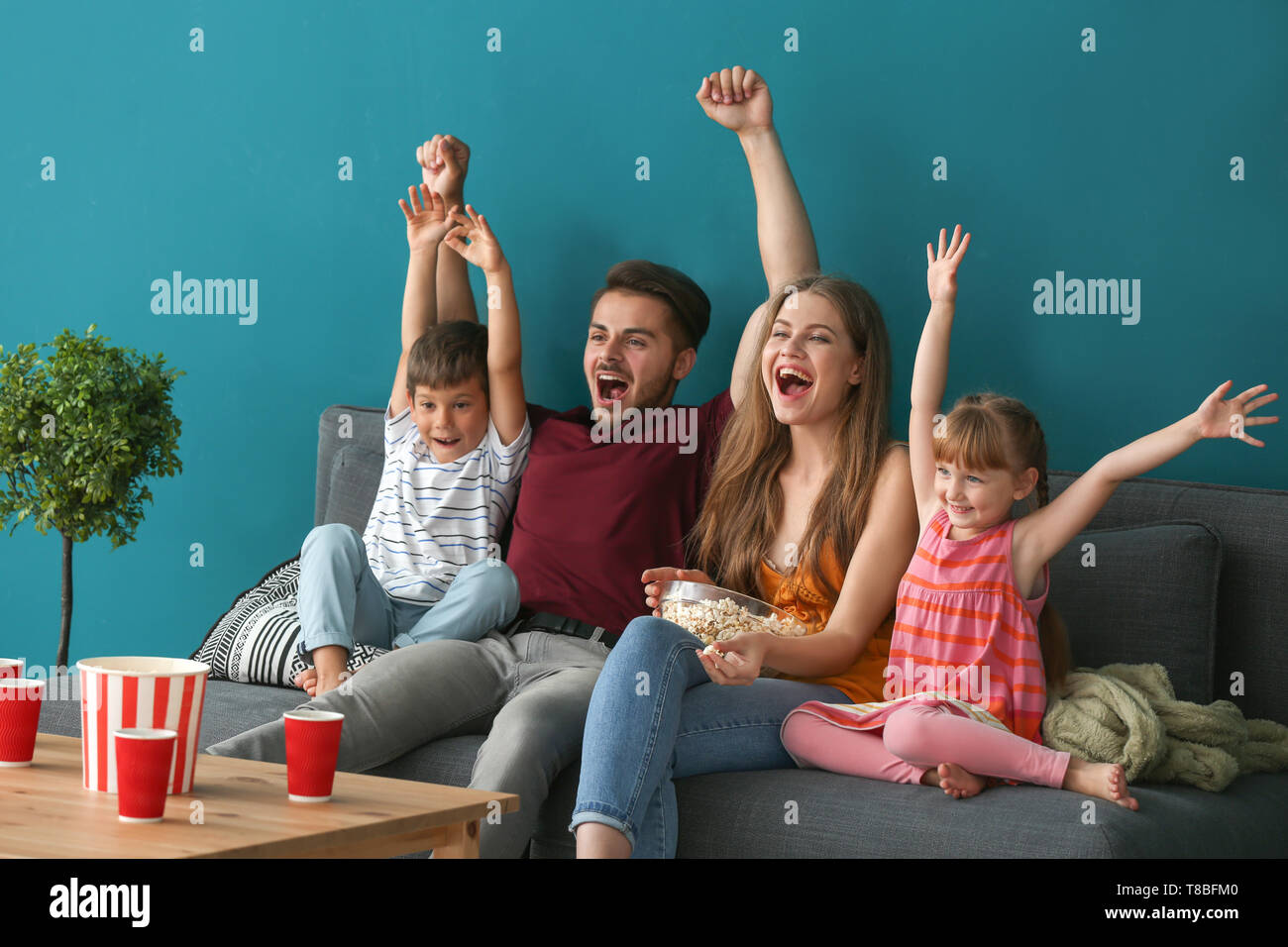 Happy family watching TV on sofa at home Stock Photo - Alamy