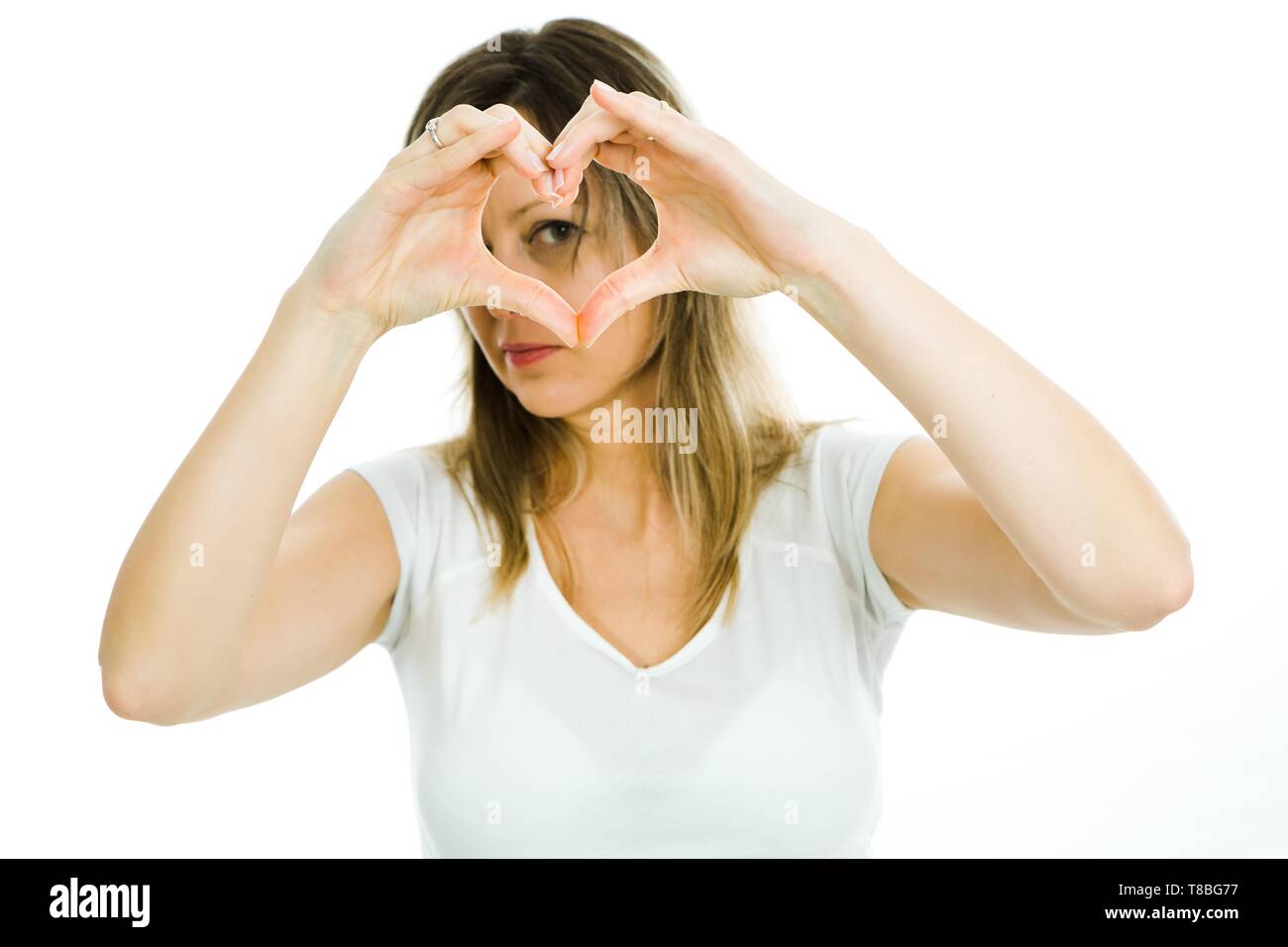 Blond woman shows symbol of love - heart shape with hands - looking ...