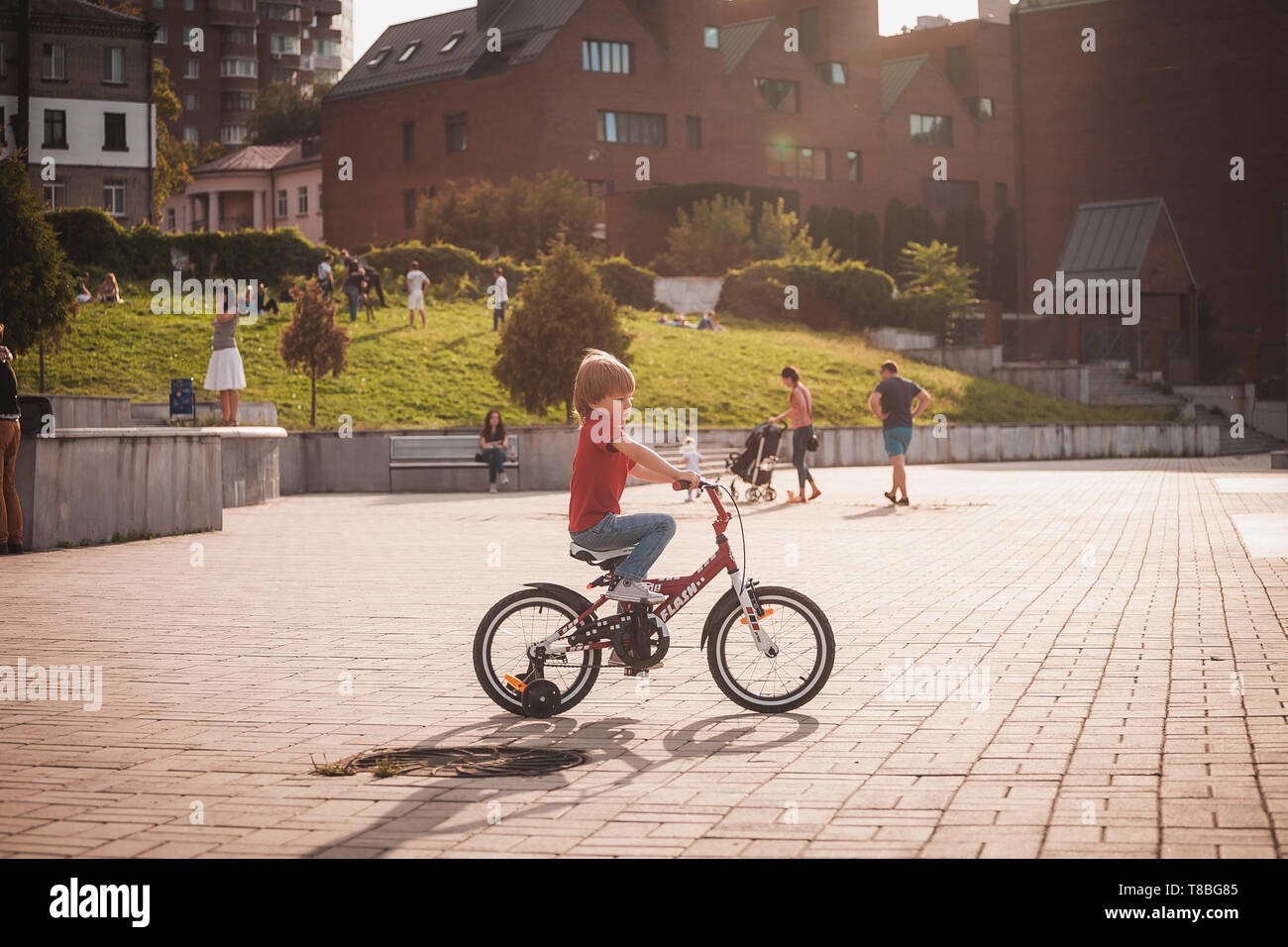 little boy in red t-shirt riding bike in park, warm sunset sun Stock ...