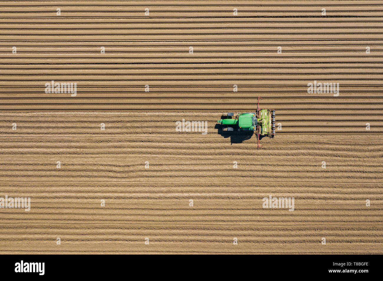 Aerial view of farming tractor plowing and spraying on field ...