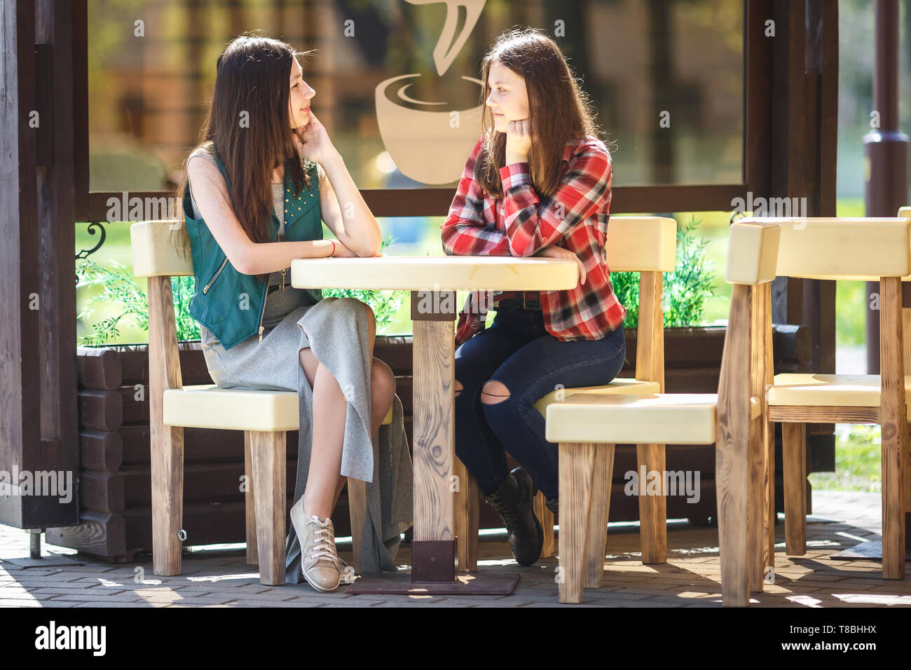two young girls friends sit and talk at a table in a city cafe Stock ...