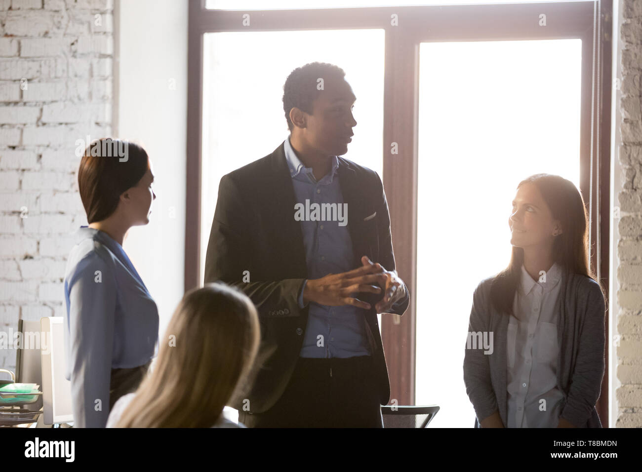 Black boss giving instructions to employees during briefing at office ...