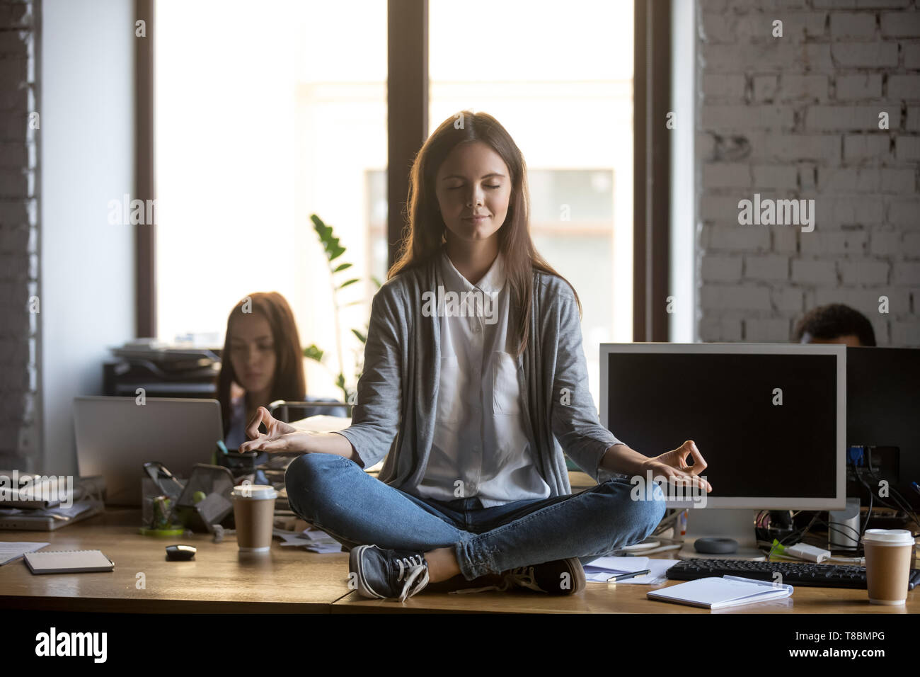 Focused office worker sitting at desk and meditating Stock Photo - Alamy