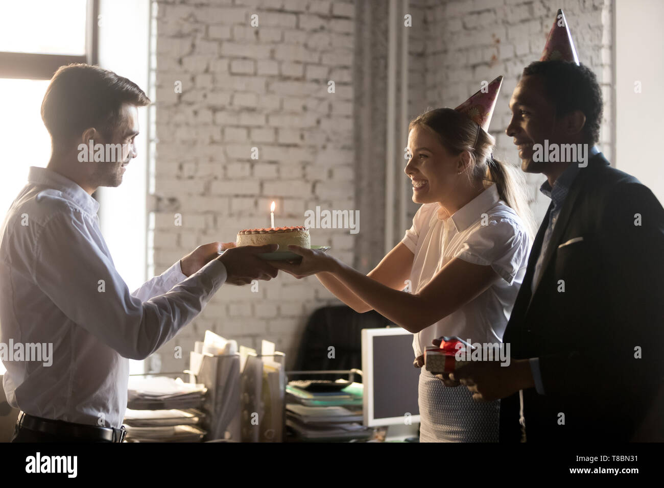 Diverse colleagues congratulating workmate with birthday giving cake ...