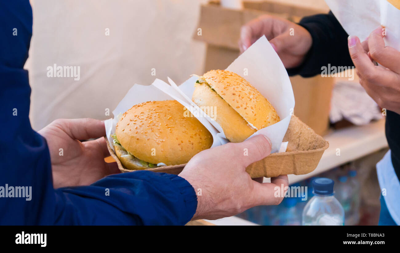 Man taking burgers at street food festival Stock Photo - Alamy