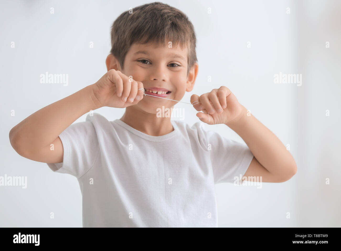 Cute little boy flossing his teeth on light background Stock Photo - Alamy