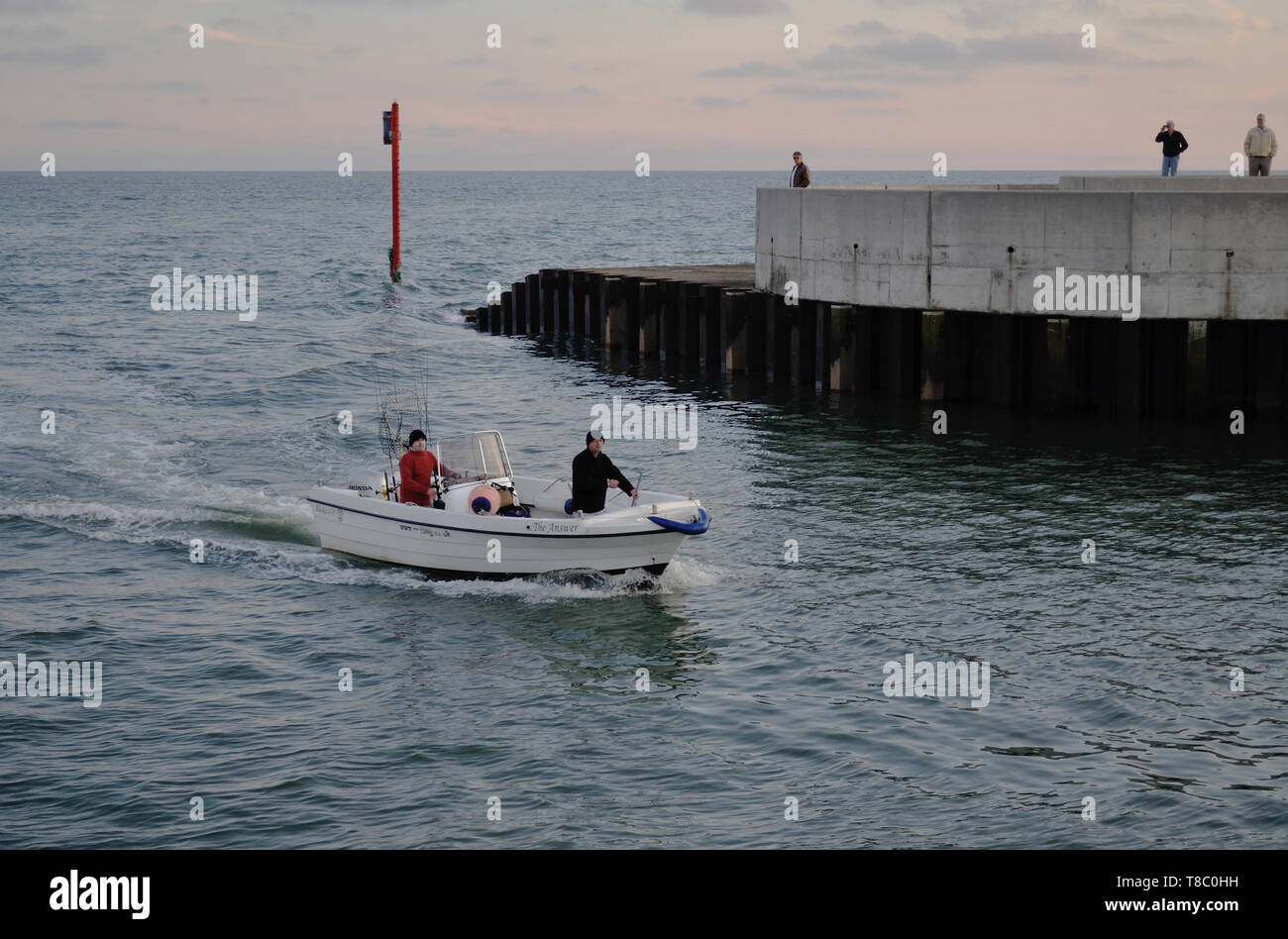 A small fishing boat returns to the harbour at West Bay, Dorset Stock ...