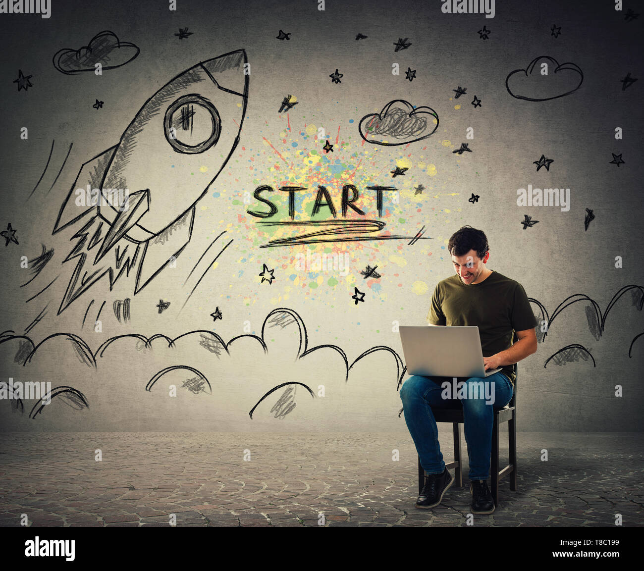 Creative young man freelancer working on laptop seated on a chair ...