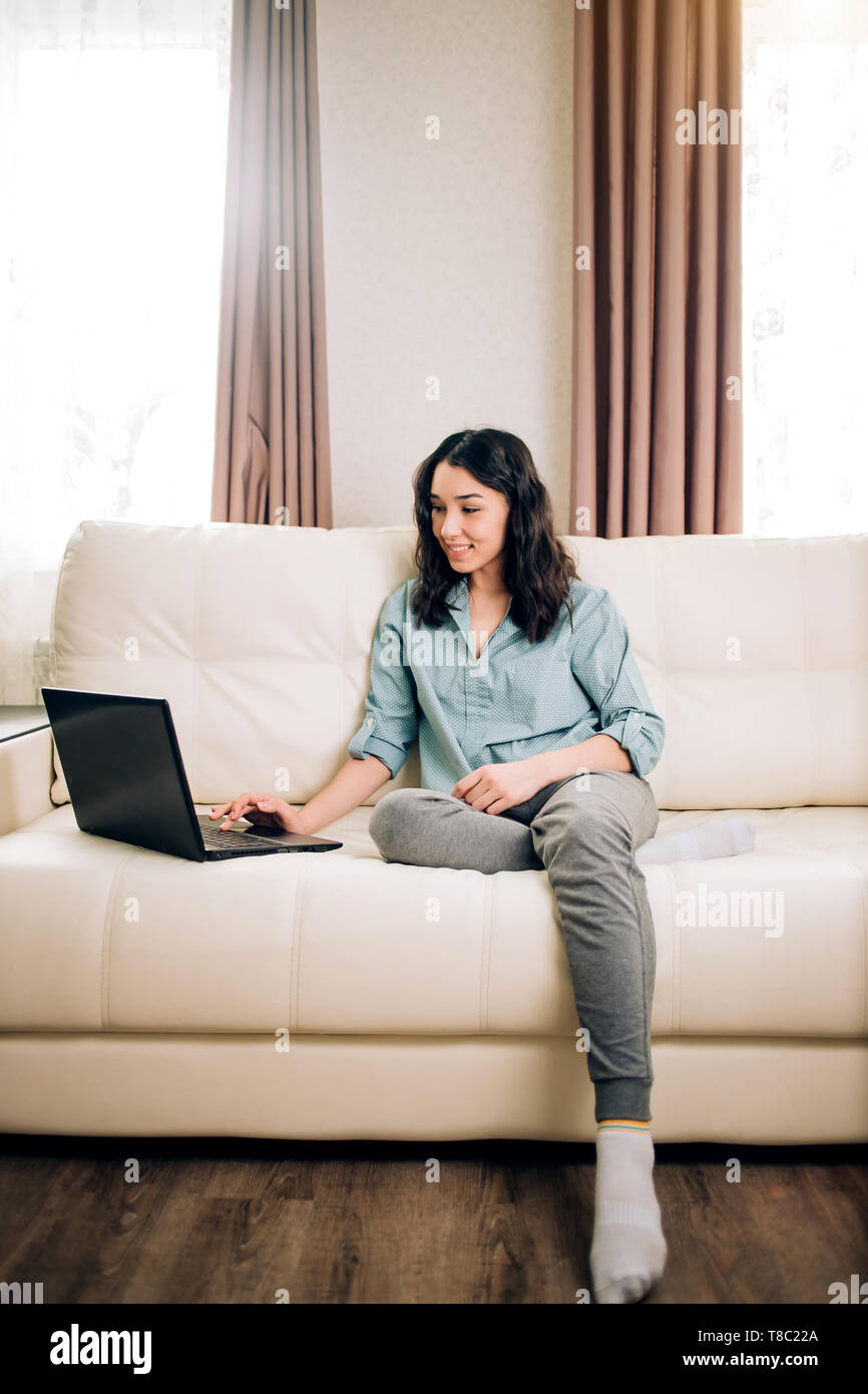 Full length portrait of brunette sitting with laptop computer, laughing ...