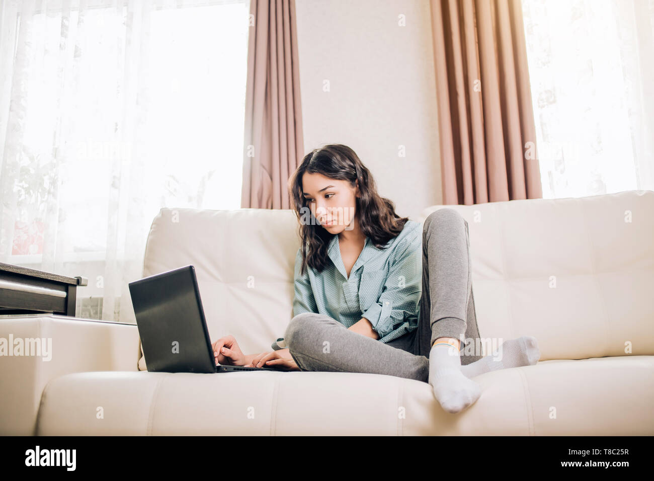 Full length portrait of brunette sitting with laptop computer, laughing ...