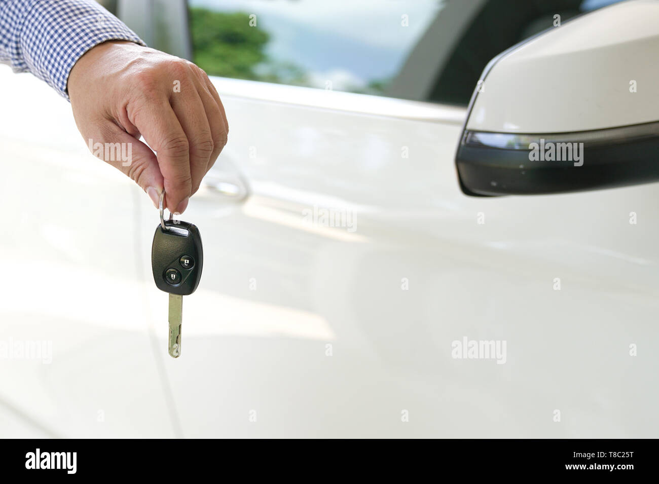 Male hand holding a car key in front of a car, a transport concept ...