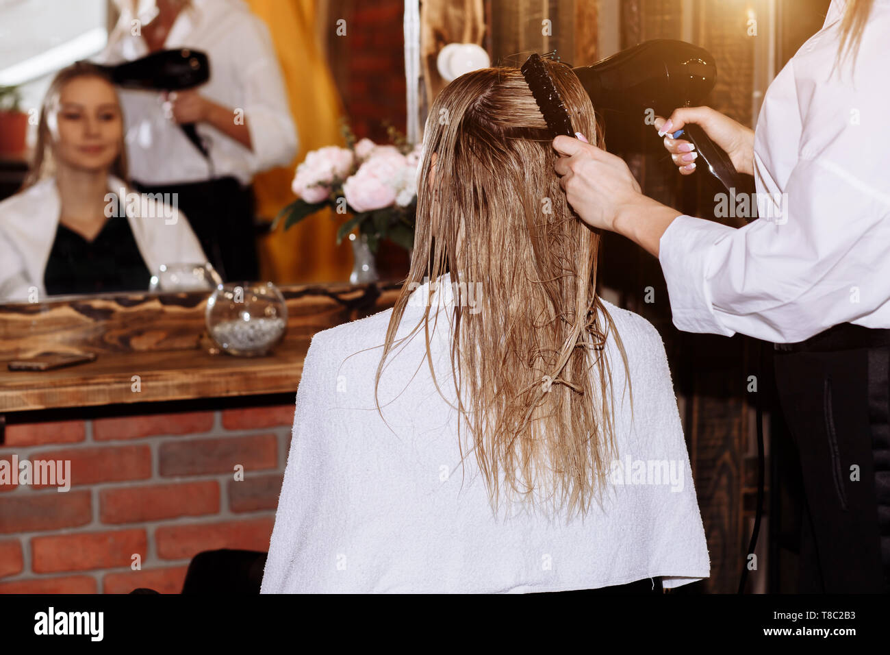 Cute beautiful hairdresser making hairstyle to young woman after ...