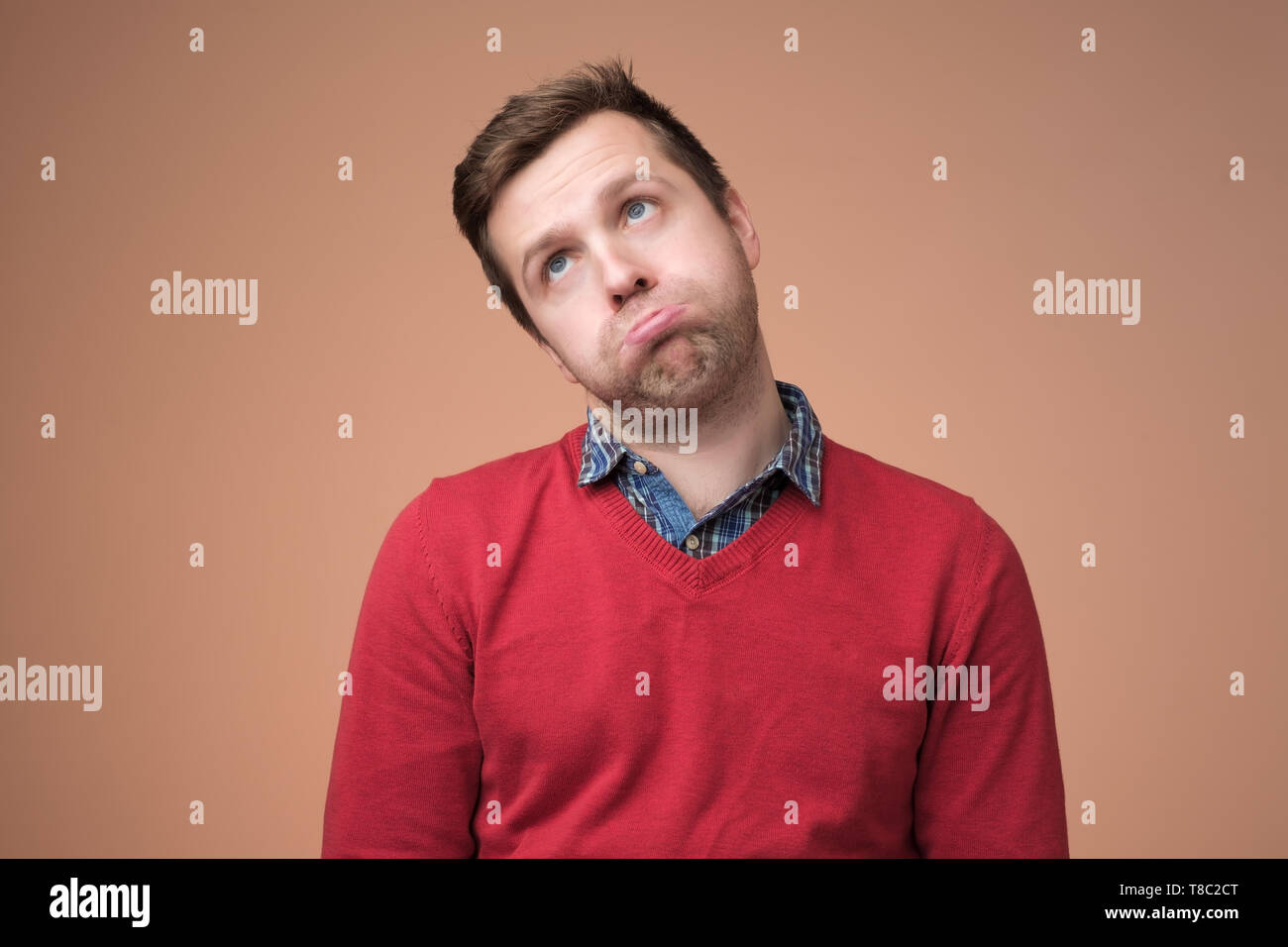 man in red sweater puffing his cheeks, feeling fed up as heis tired ...