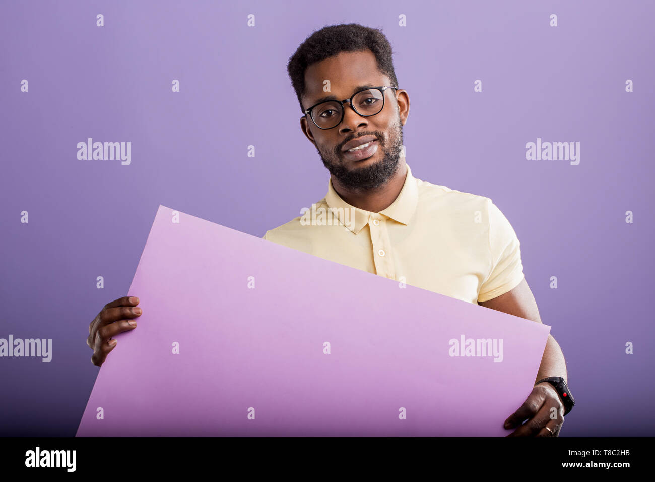 Picture of young african american man holding lilac blank board looking ...