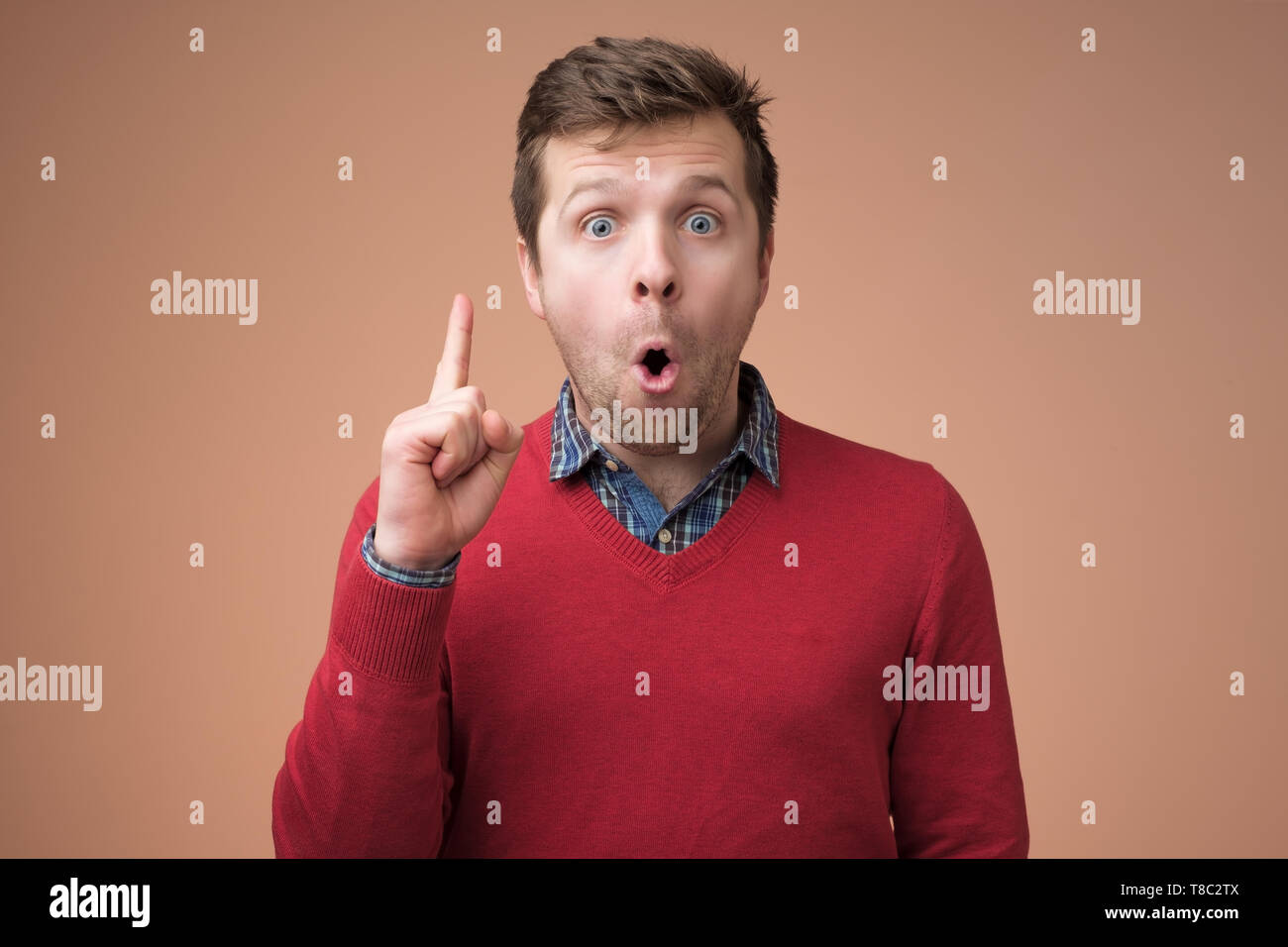 Attractive young man in red sweater pointing up with his finger Stock ...