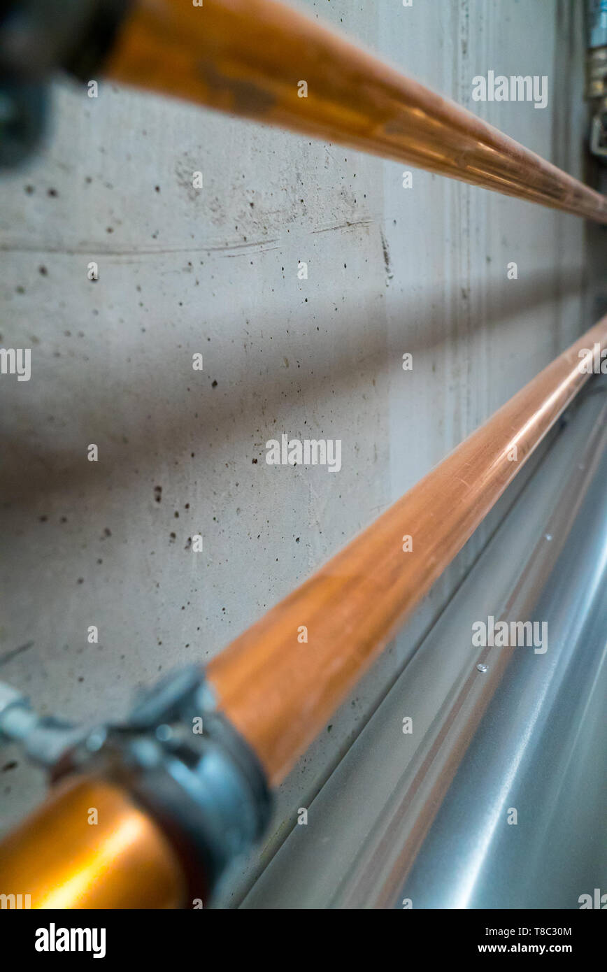 horizontal view of long new shiny copper pipes leading along a concrete ...
