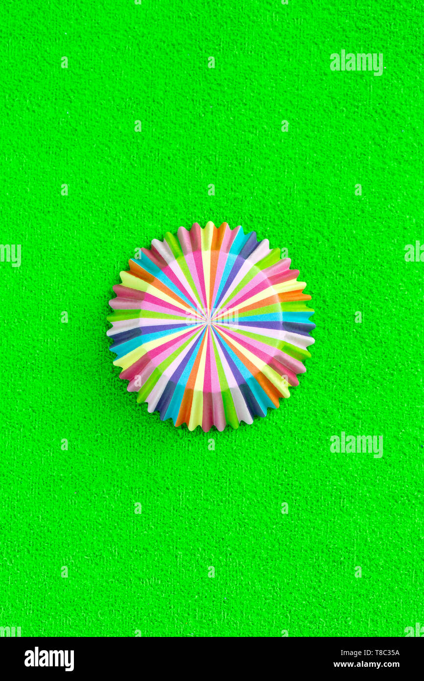 Rainbow colored paper baking cups for muffins and cupcakes on a green ...