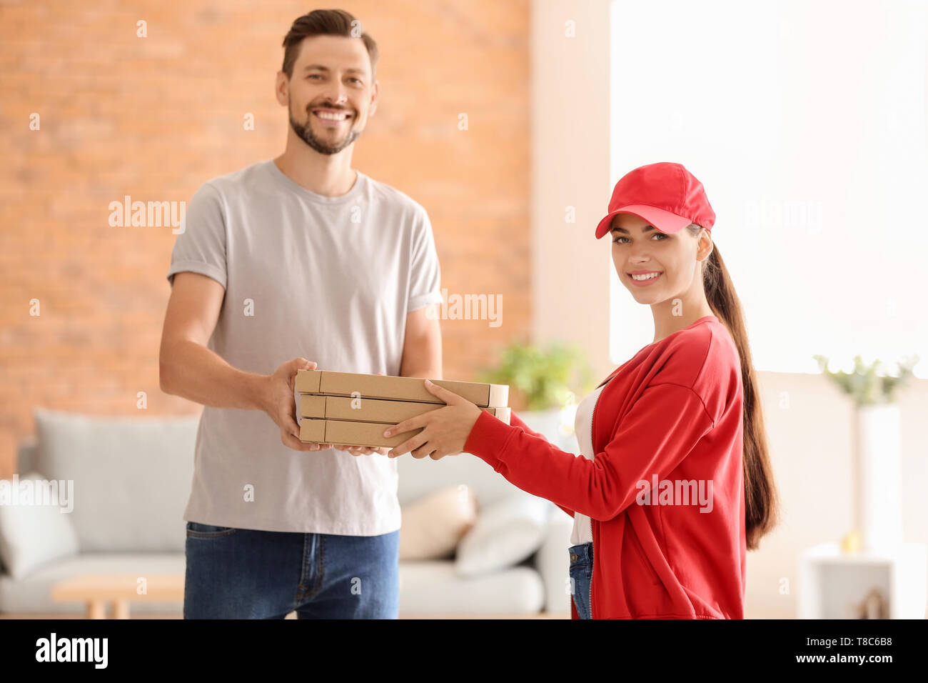Young woman delivering pizza to customer indoors Stock Photo - Alamy