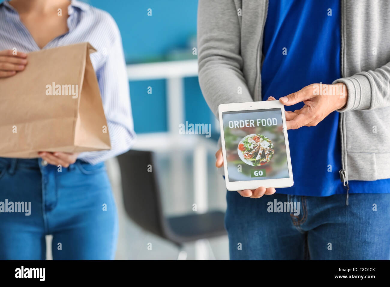 Young worker of food delivery service with tablet computer and customer ...