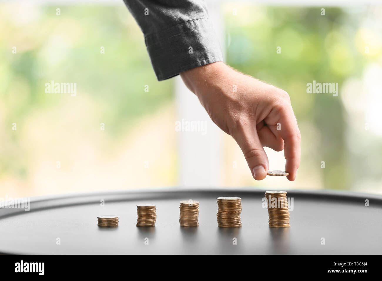 Man stacking coins on table. Savings concept Stock Photo - Alamy