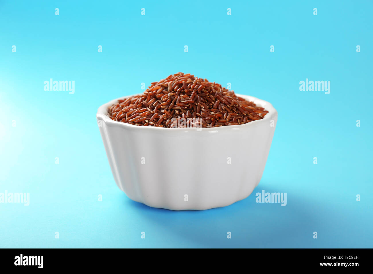 Bowl with raw red rice on color background Stock Photo - Alamy