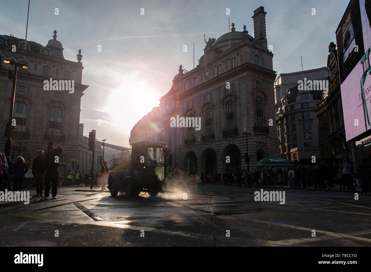 A street cleaner cleans the streets around Piccadilly Circus at dusk ...