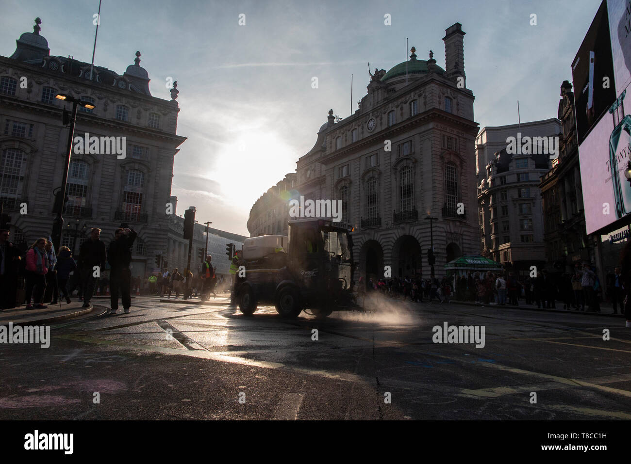 A street cleaner cleans the streets around Piccadilly Circus at dusk ...
