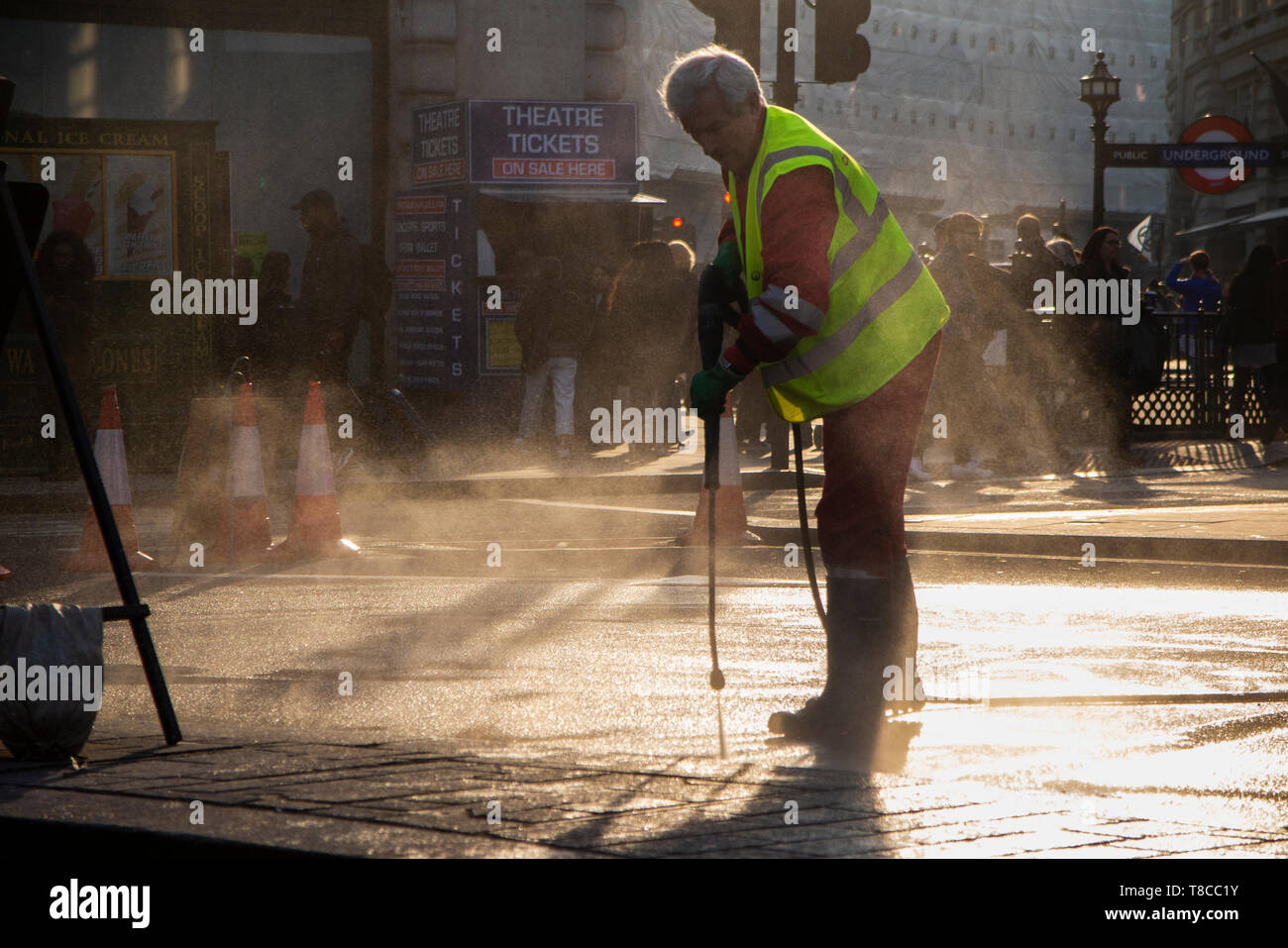 A street cleaner cleans the streets around Piccadilly Circus at dusk ...