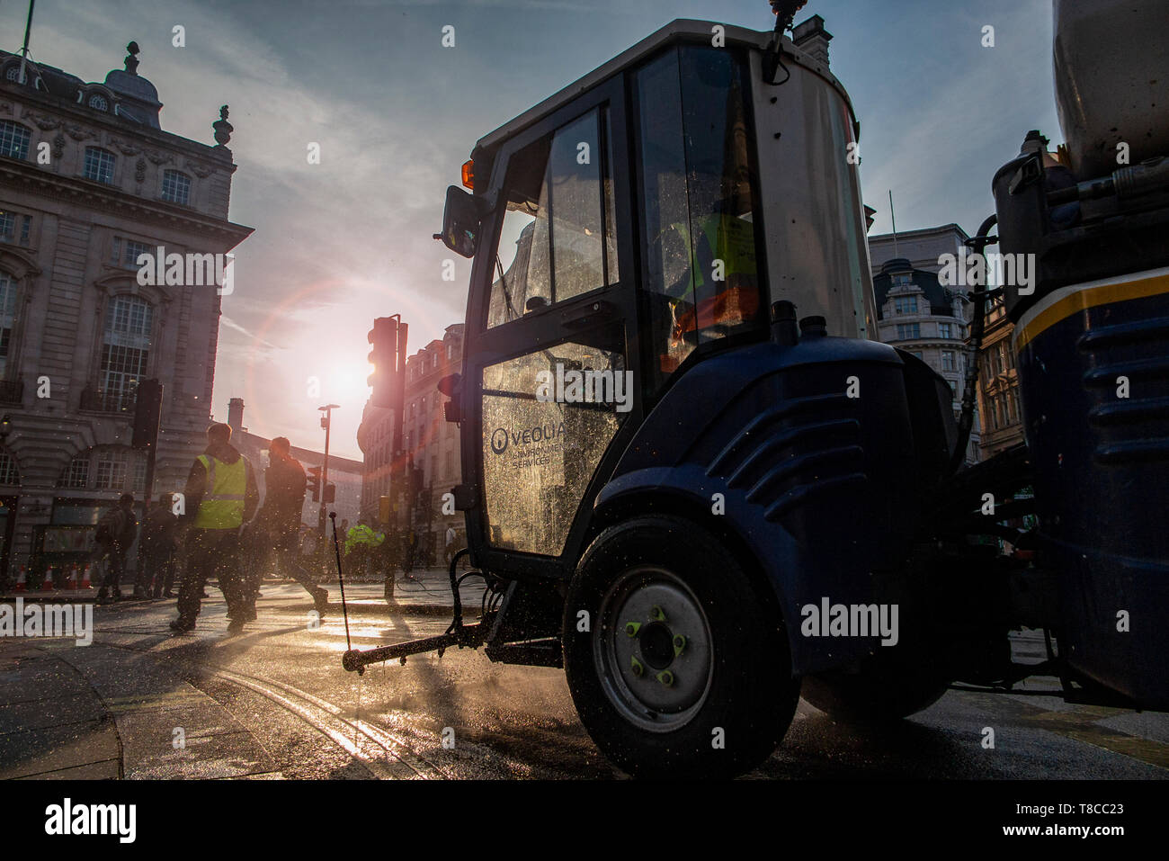 A street cleaner cleans the streets around Piccadilly Circus at dusk ...