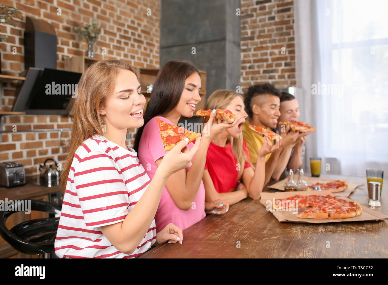 Young people eating delicious pizza indoors Stock Photo - Alamy