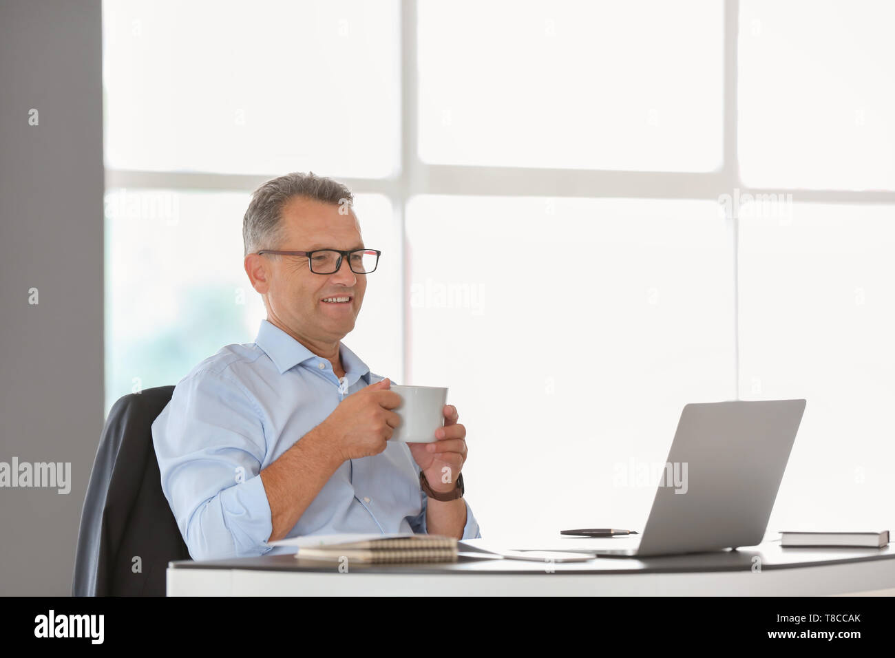 Mature businessman drinking coffee at workplace in office Stock Photo ...
