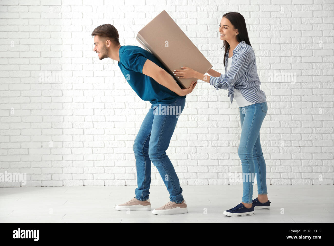 Young couple carrying big moving box at new home Stock Photo - Alamy
