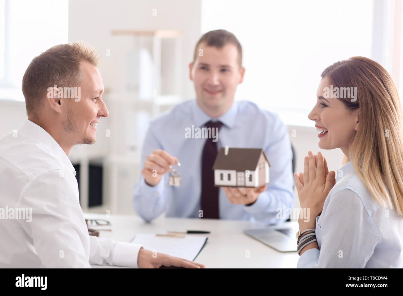 Real estate agent showing house model to clients in his office Stock ...