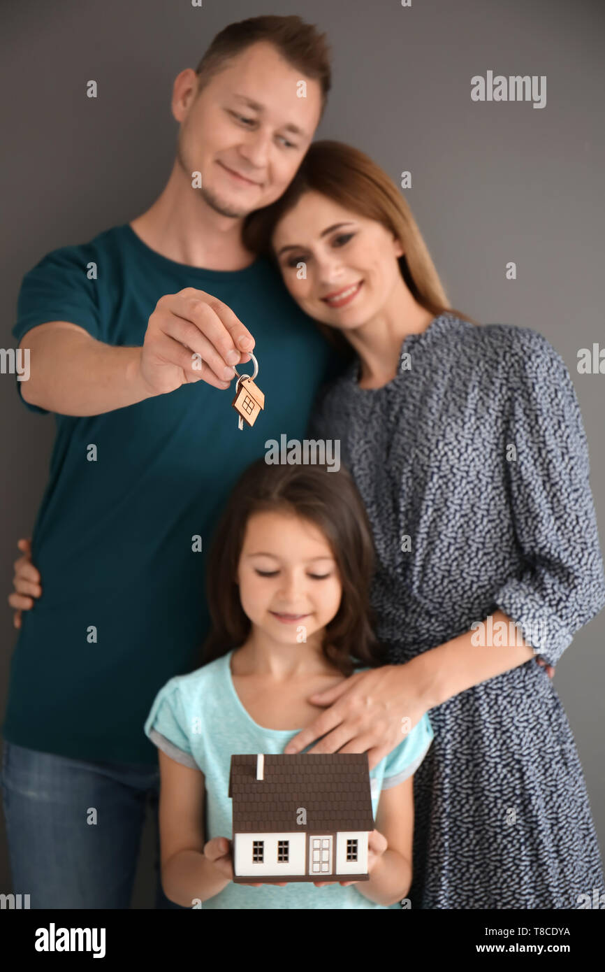 Happy family with house model and key of their new home on grey ...