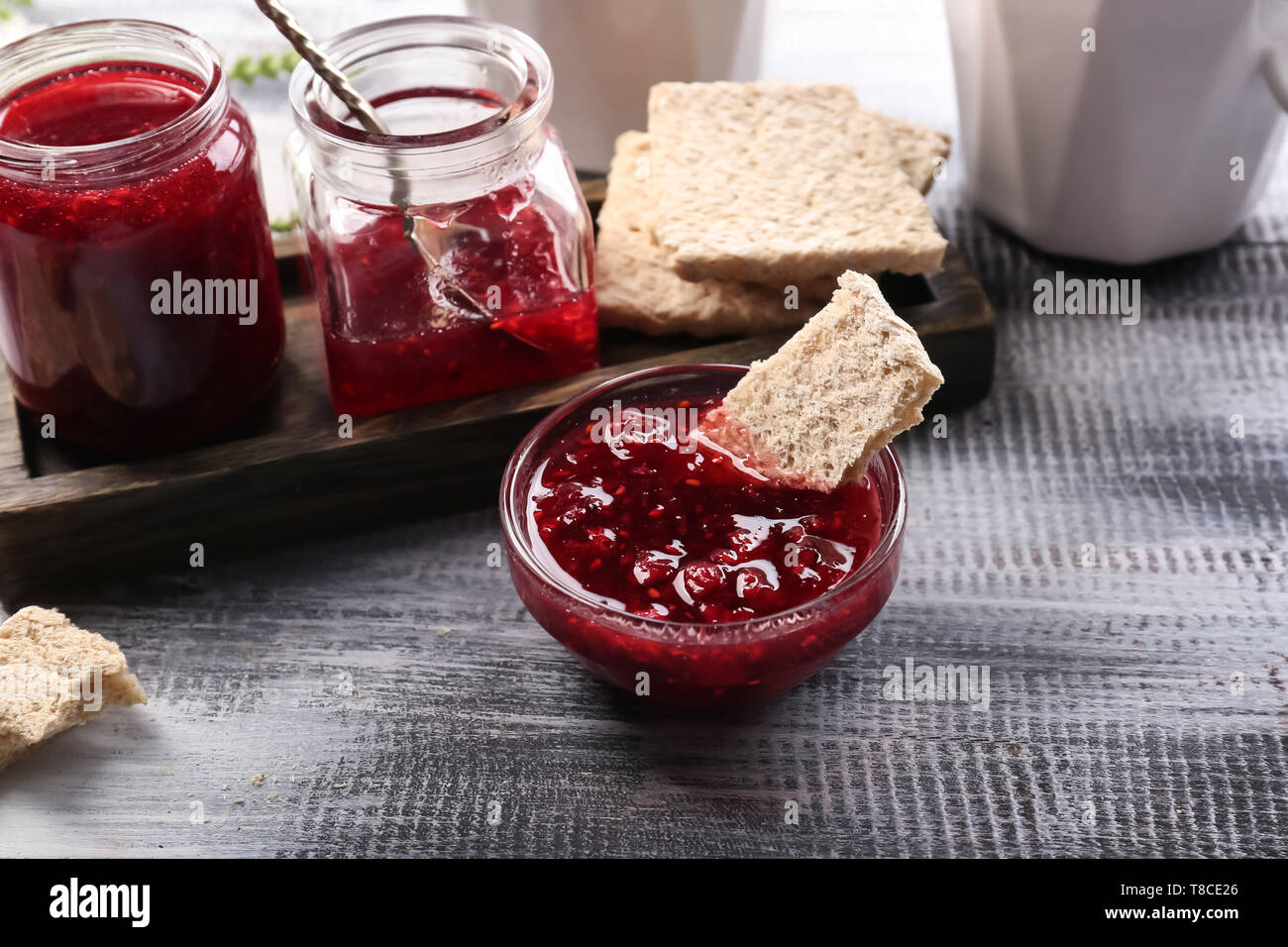 Composition with glass jars and bowl of tasty raspberry jam on wooden ...