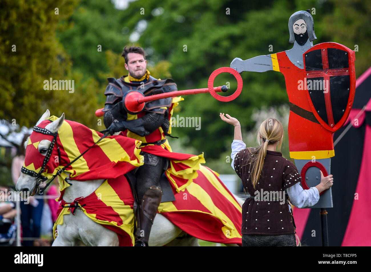 A woman throws a hoop for the red knight to spear with his lance during ...