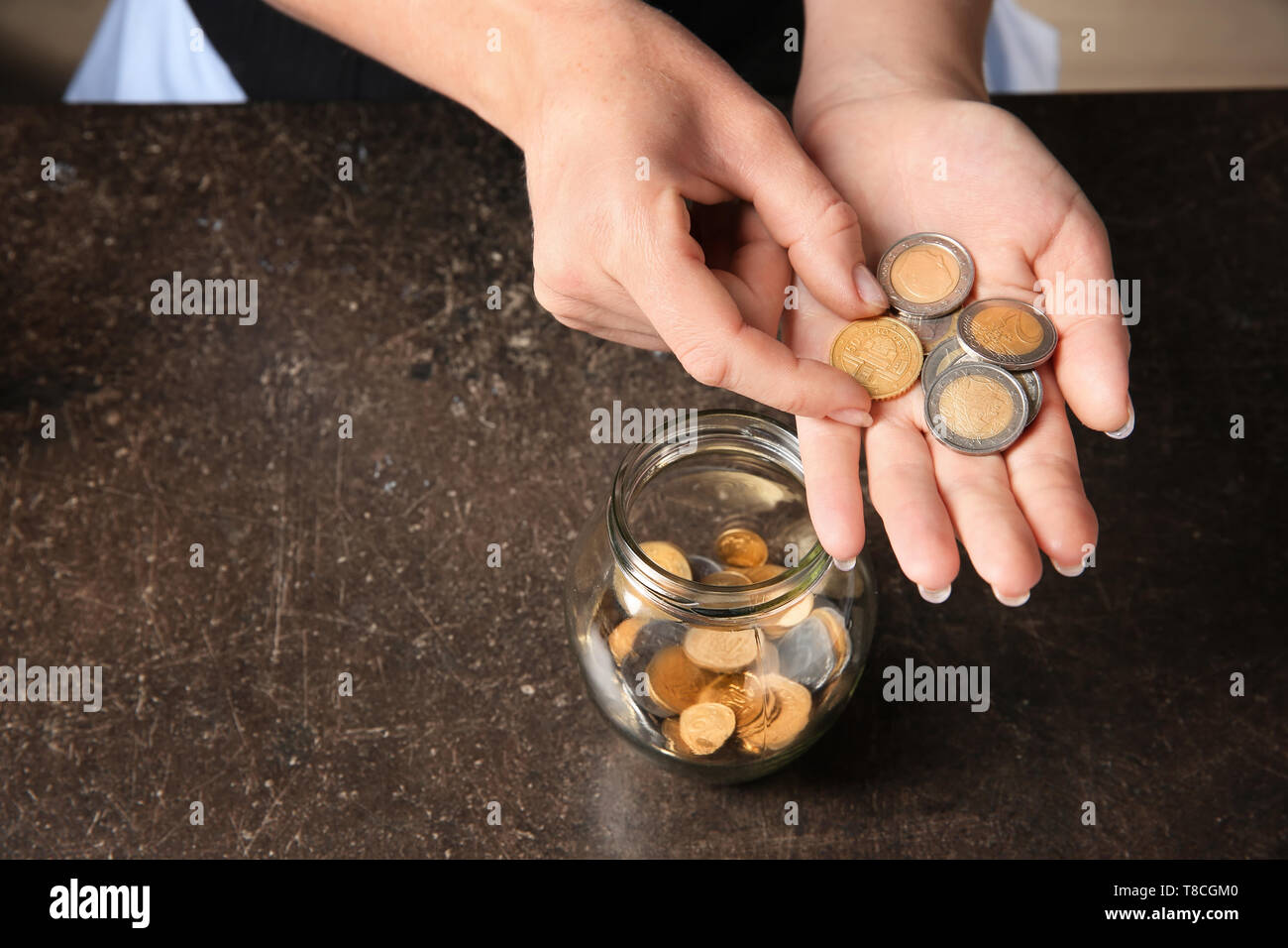 Woman putting coins into jar hi-res stock photography and images - Alamy