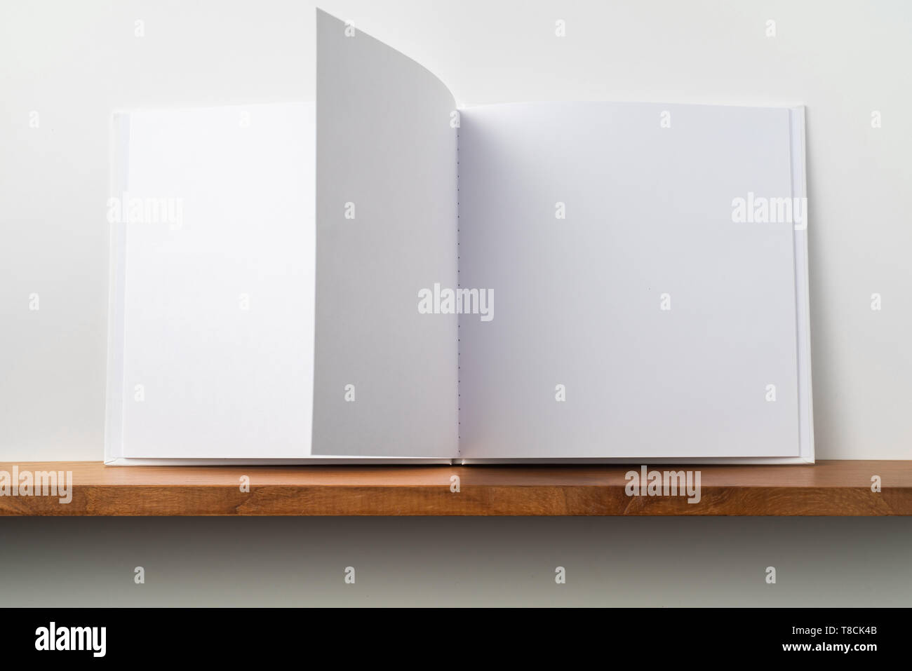 Design concept - front view of open square white notebook on bookshelf ...