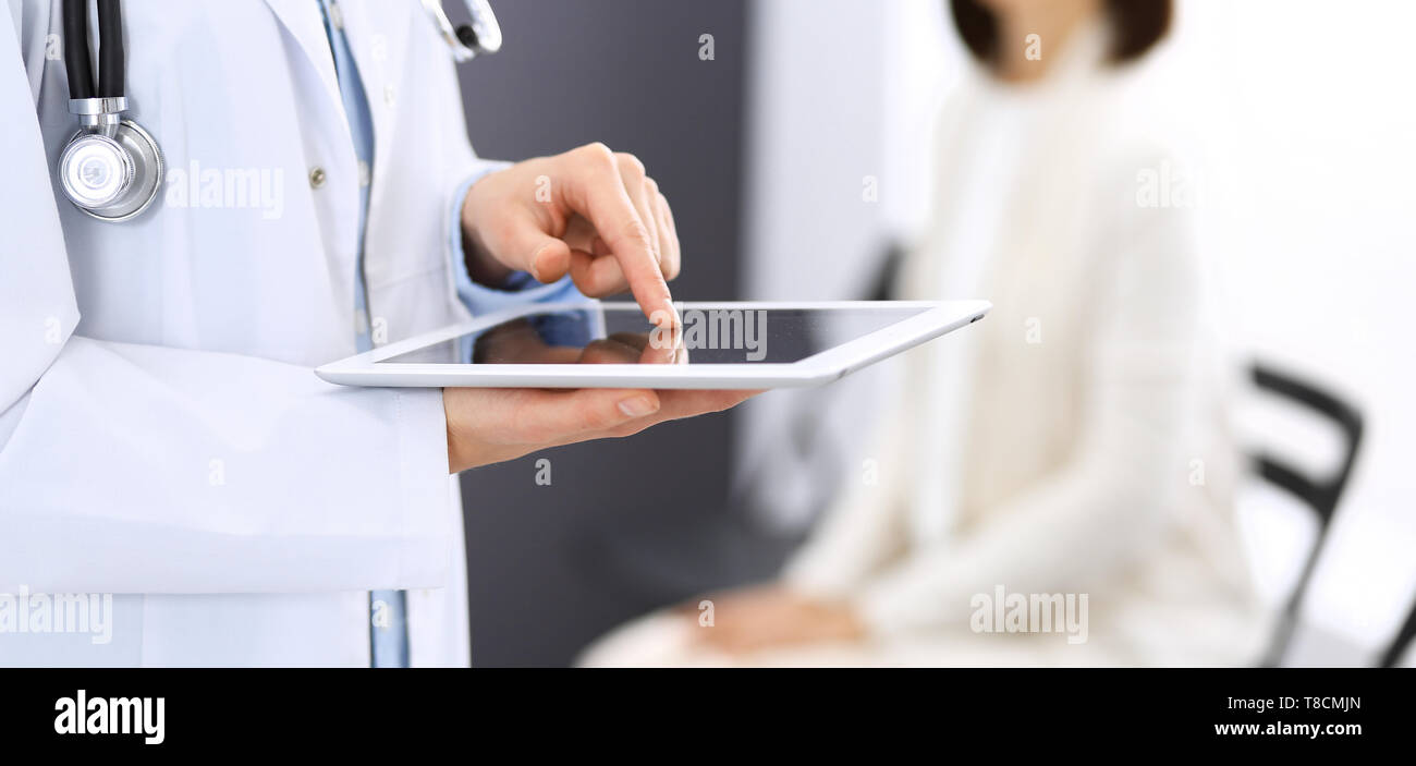 Female physician using digital tablet while standing near reception ...