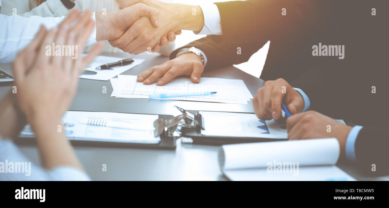 Business people shaking hands at meeting while theirs colleagues ...