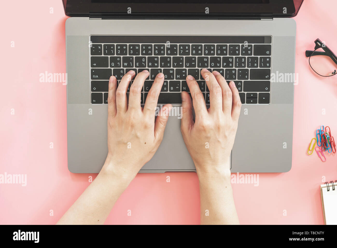 Girl typing on laptop in pink pastel colourful office with accessories ...