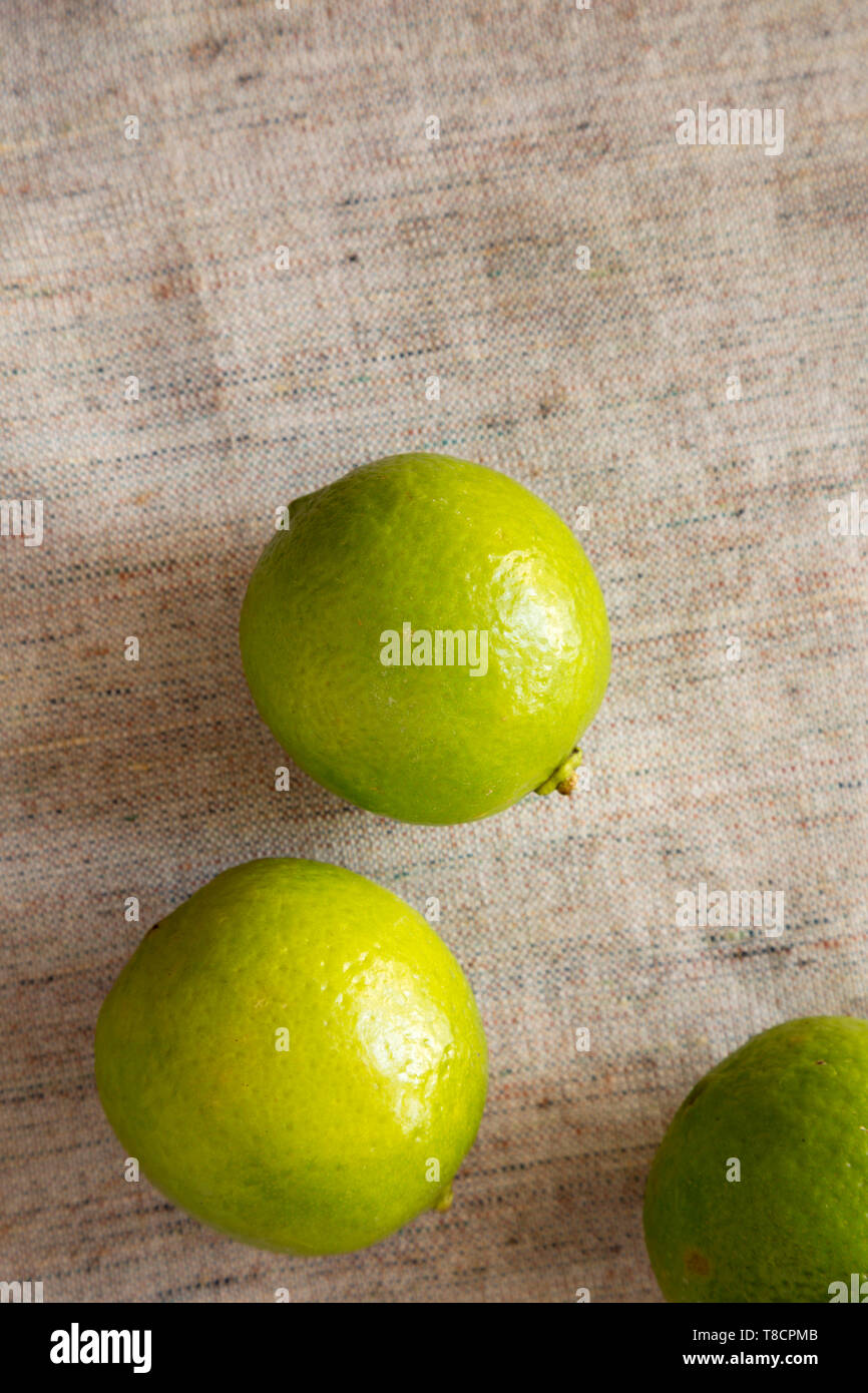 Green citrus limes on cloth, top view. From above, overhead, flat lay ...