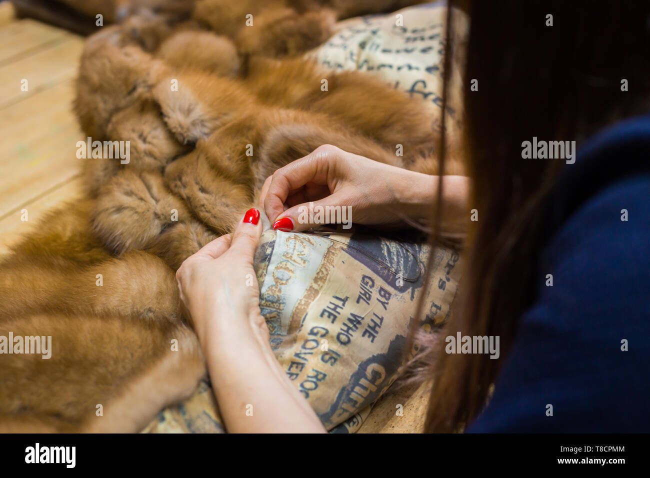 Professional tailor, designer repairing fur coat at atelier, studio ...
