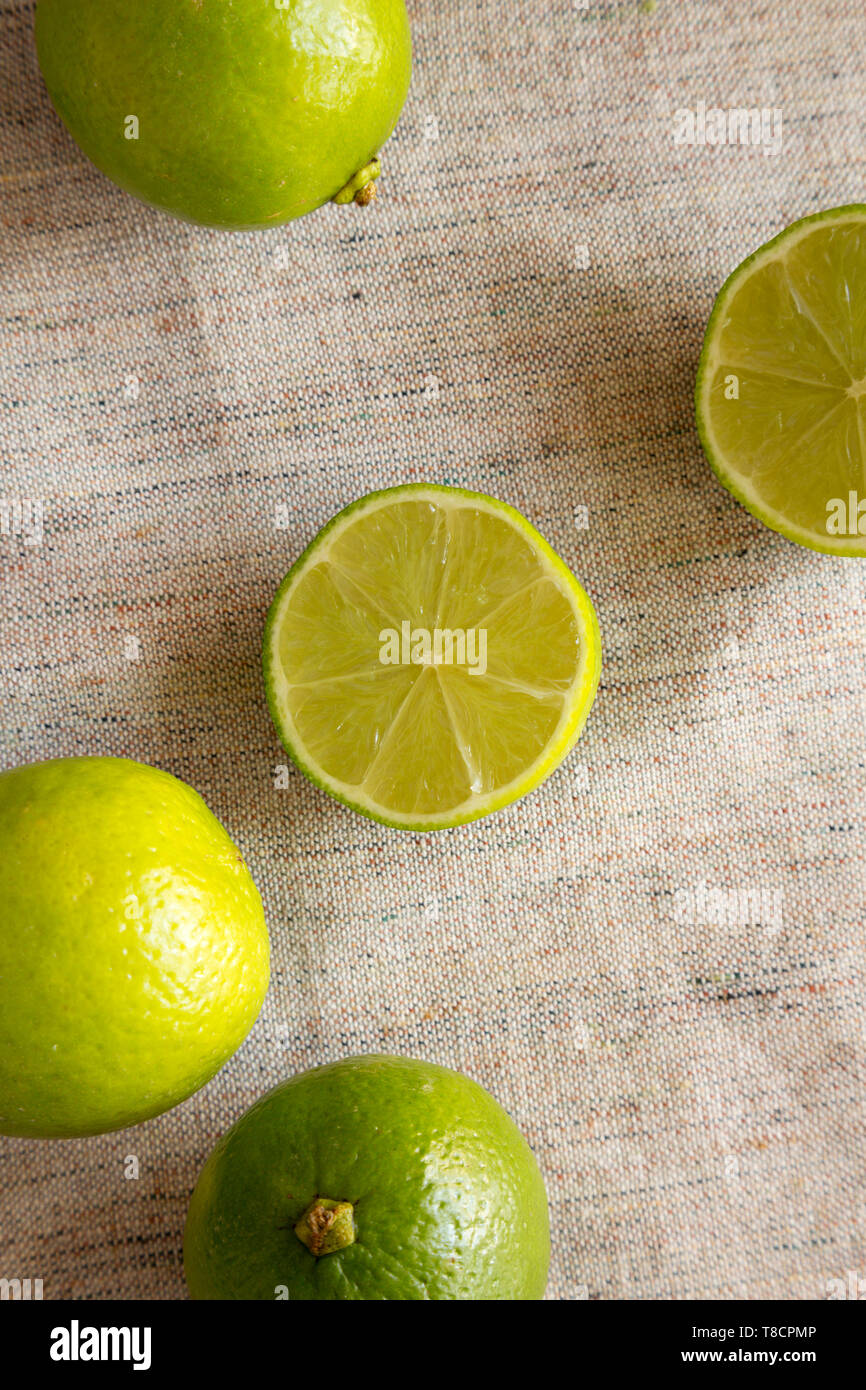 Green citrus limes on cloth, top view. From above, overhead, flat lay ...