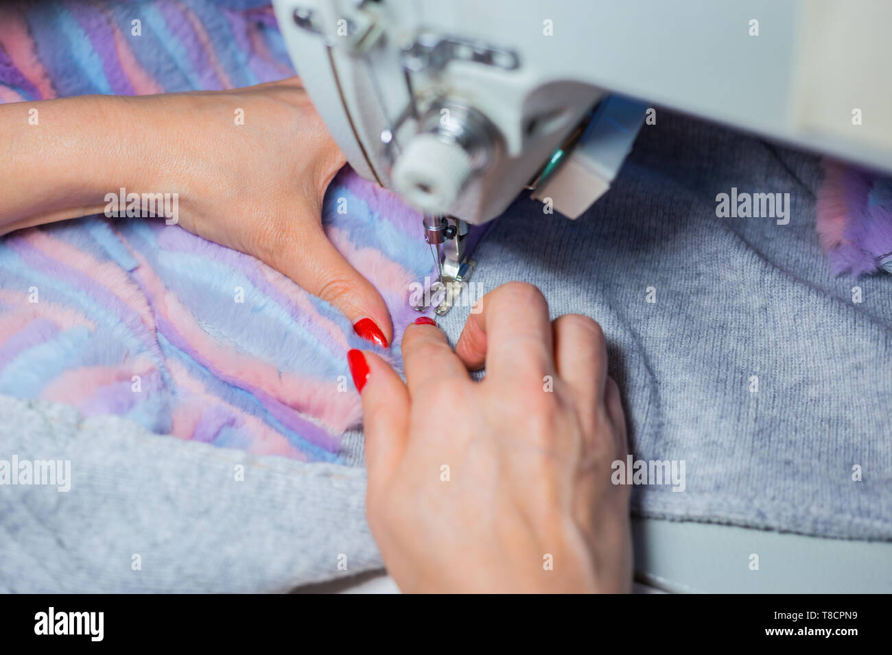 Close up shot - professional tailor, fashion designer sewing colorful ...