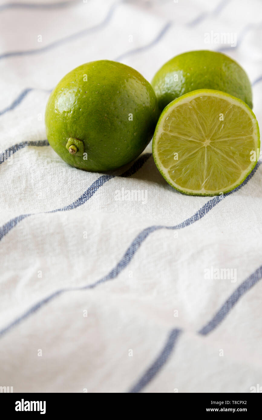 Whole and cut green citrus limes on cloth, side view. Close-up Stock ...