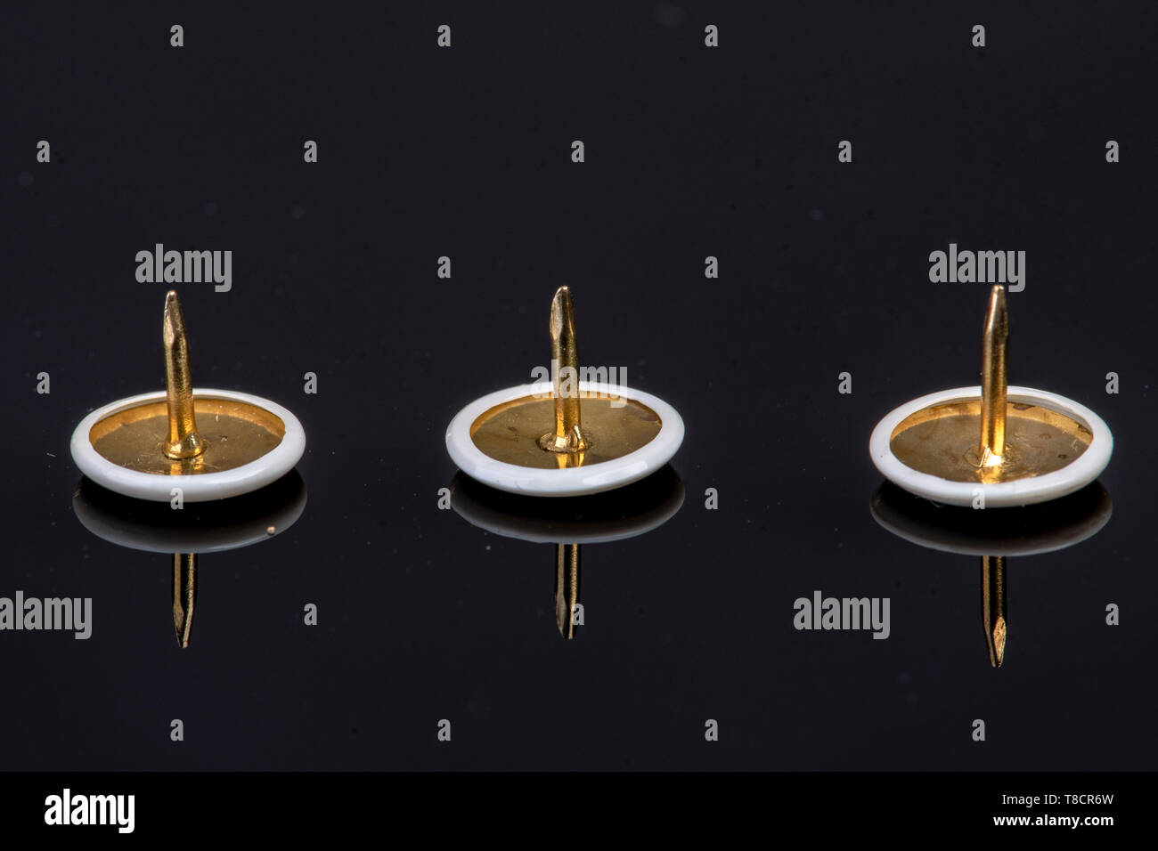 three white pins on a black background with the tip up sharp and ...
