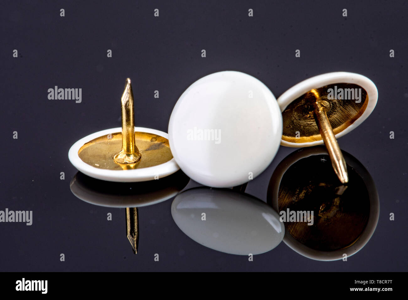 three white drawing pins on a black background with the tip pointing ...