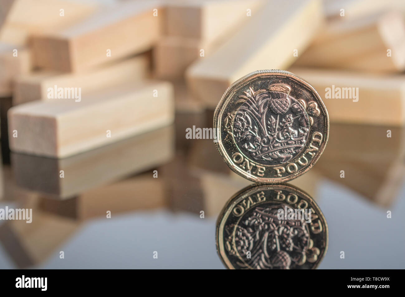 UK New Pound coin on reflective background with scattered wood bricks ...