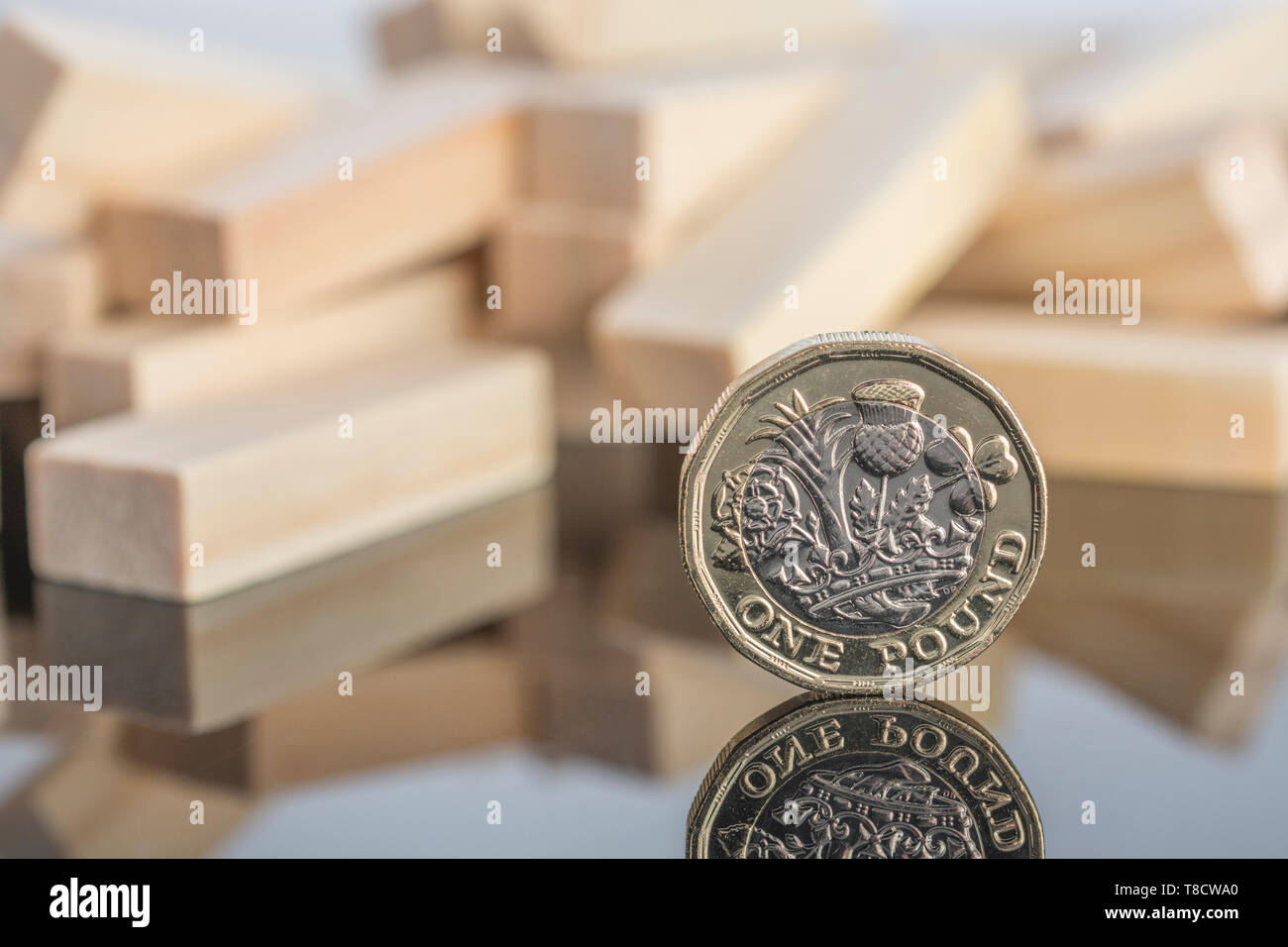 UK New Pound coin on reflective background with scattered wood bricks ...